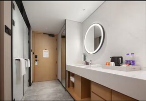 Uma casa de banho moderna com um espelho grande, uma pia e uma máquina de café.