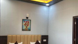 Quarto de hotel com uma cama grande, um ventilador de teto, uma luminária na parede e uma pintura de flores.