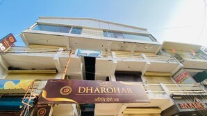 Um edifício com uma placa indicando "Dharohar Homestay", anunciando quartos com ar condicionado.