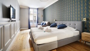 Um quarto moderno com uma cama grande, uma televisão na parede e papel de parede estampado.