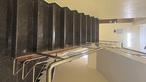 Um interior moderno com escada, corrimãos de metal e parede em tons claros.