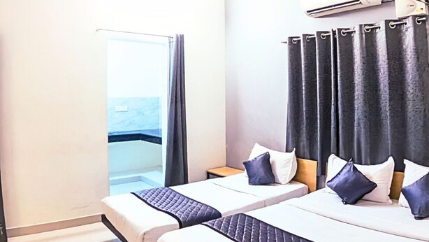 Quarto de hotel com duas camas, um ventilador de teto, aparelho de ar condicionado e vista para o mar através de uma grande janela.