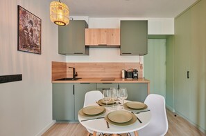 Cozinha moderna com uma mesa de jantar posta para seis pessoas, luminária pendente e armário verde.