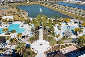 Vista aérea de um resort com várias piscinas, palmeiras e uma fonte central.