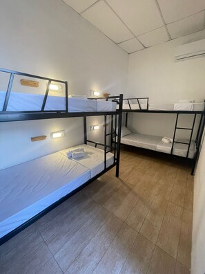 Quarto de dormitório com beliches, janela com vista e prateleira de madeira.