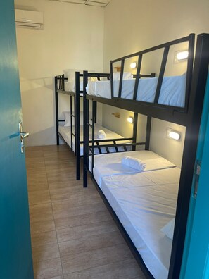 Quarto com beliches, piso de madeira e porta com puxador.