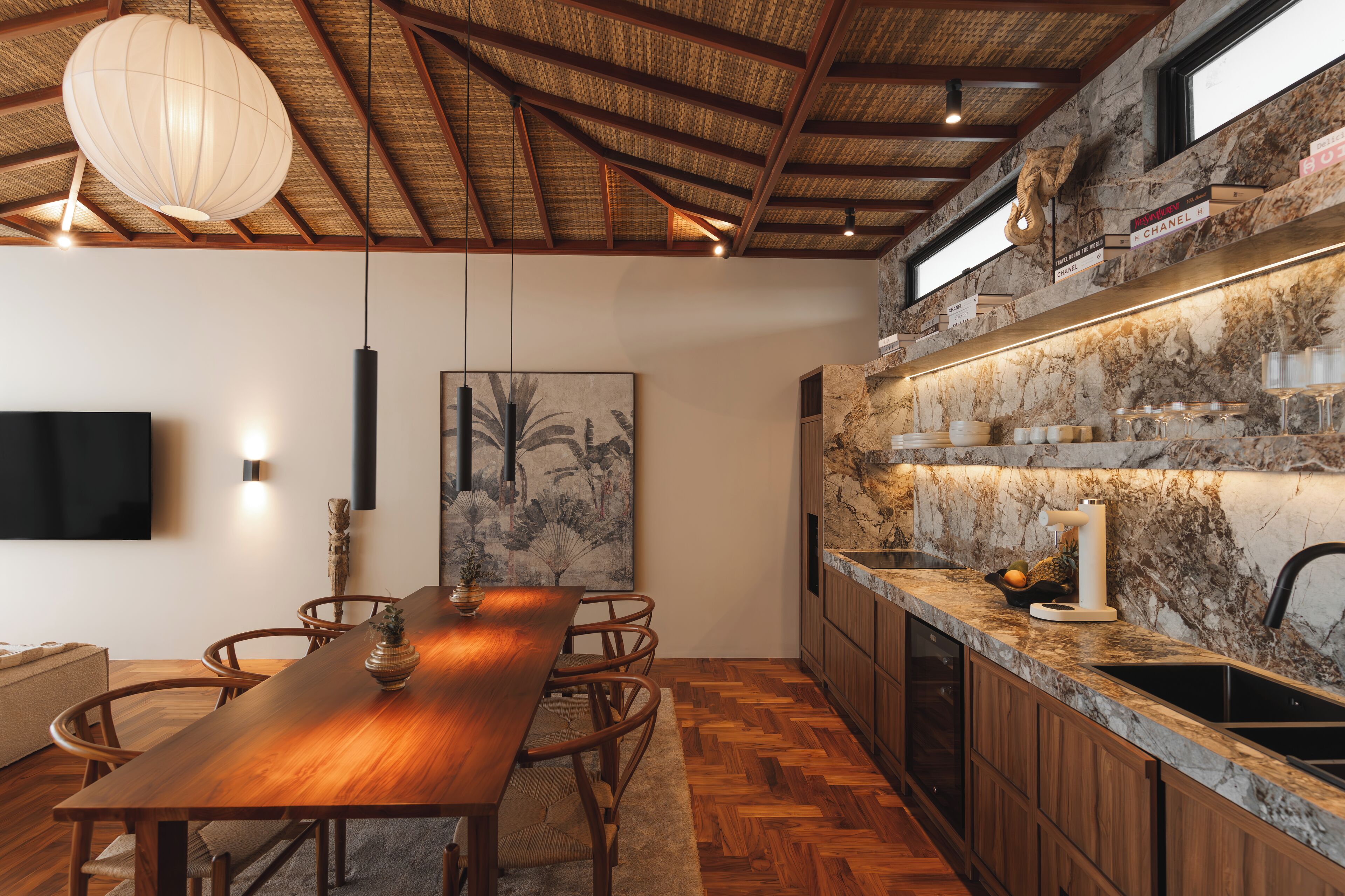 Uma cozinha moderna com mesa de jantar de madeira, uma pintura grande na parede e um revestimento de pedra.