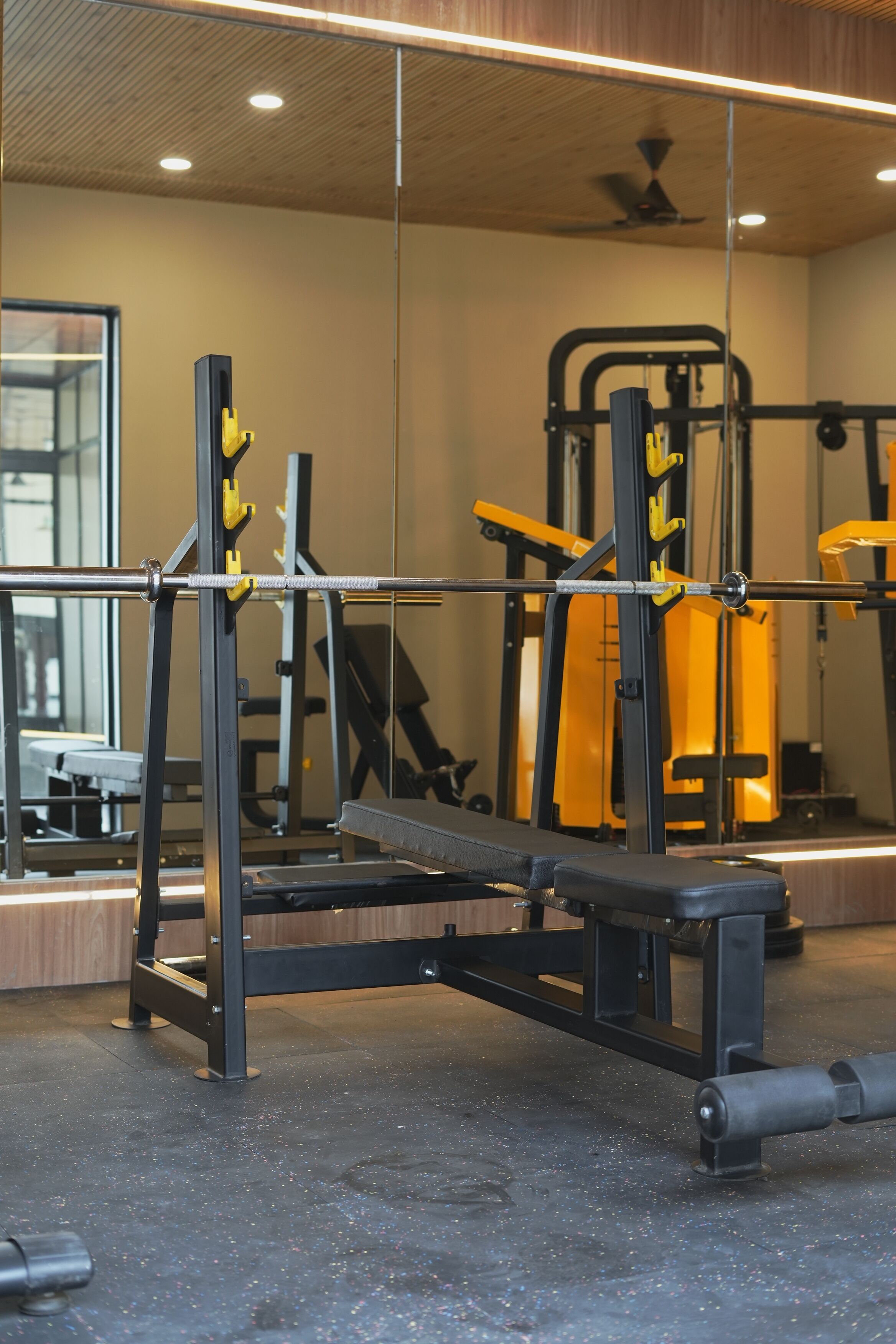 Uma academia com equipamentos de ginástica, incluindo um banco de supino e estações de musculação.