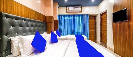 Quarto de hotel com uma cama grande, televisão de tela plana e ar-condicionado na parede.