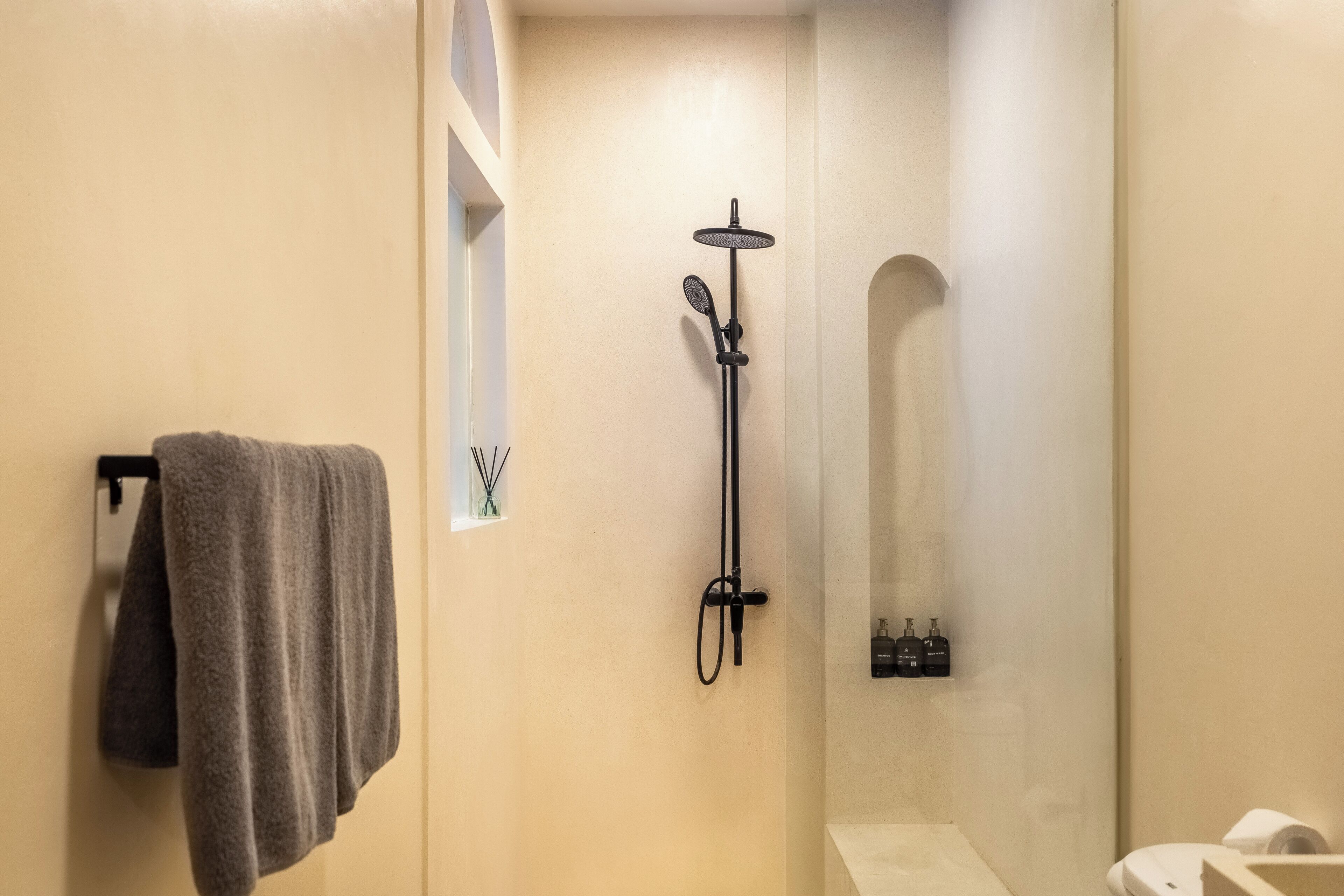 Casa de banho moderna com chuveiro, porta-toalhas e uma pequena janela.