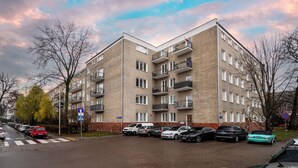 Um edifício de apartamentos com várias andares, varandas, um estacionamento e uma faixa de pedestres.