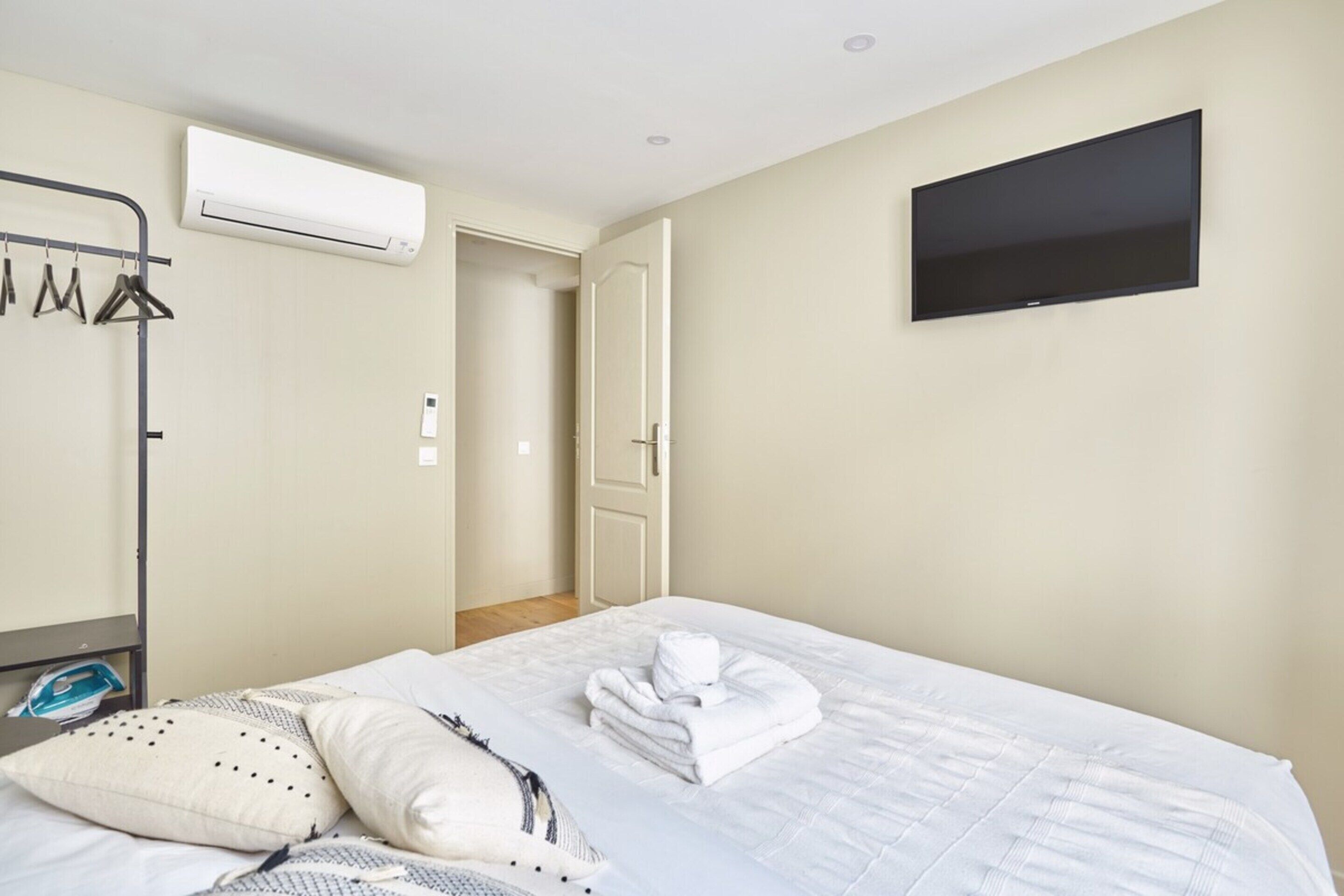 Quarto de hotel com cama, televisão na parede, guarda-roupa e ar condicionado.