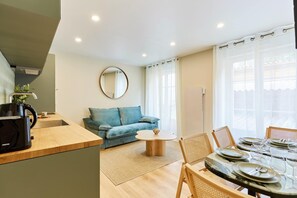 Uma sala de estar moderna com um sofá, uma mesa de centro e um espaço de jantar acomodando quatro pessoas.