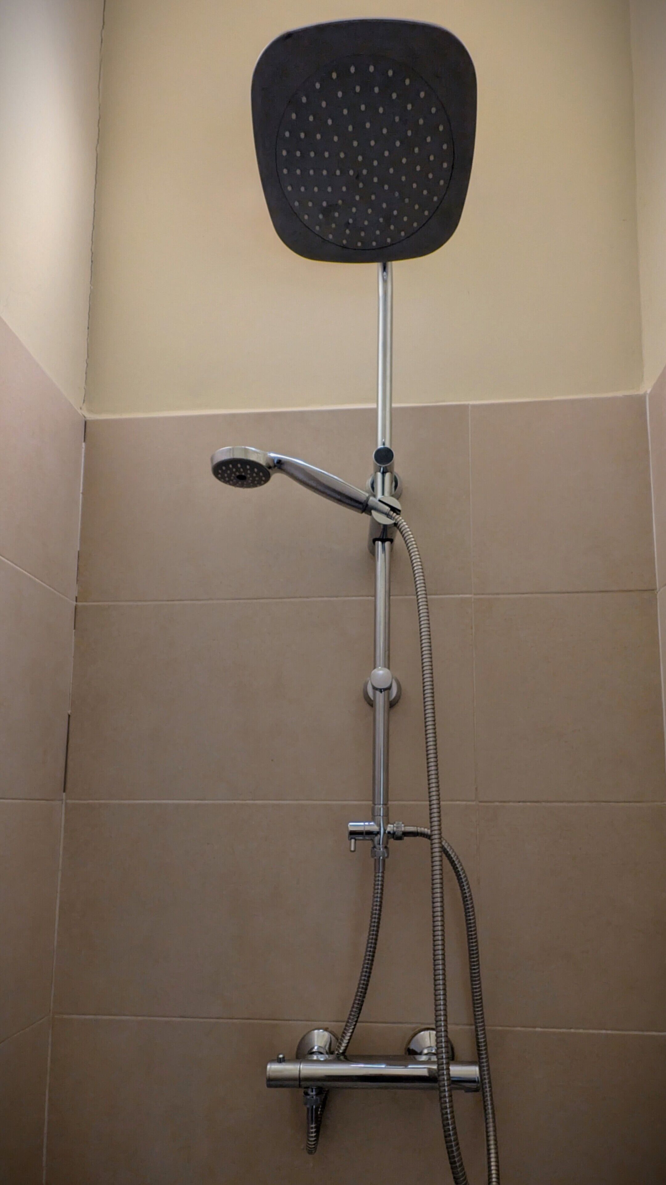 Um chuveiro com um chuveiro manual e um chuveiro de chuva fixo no teto.