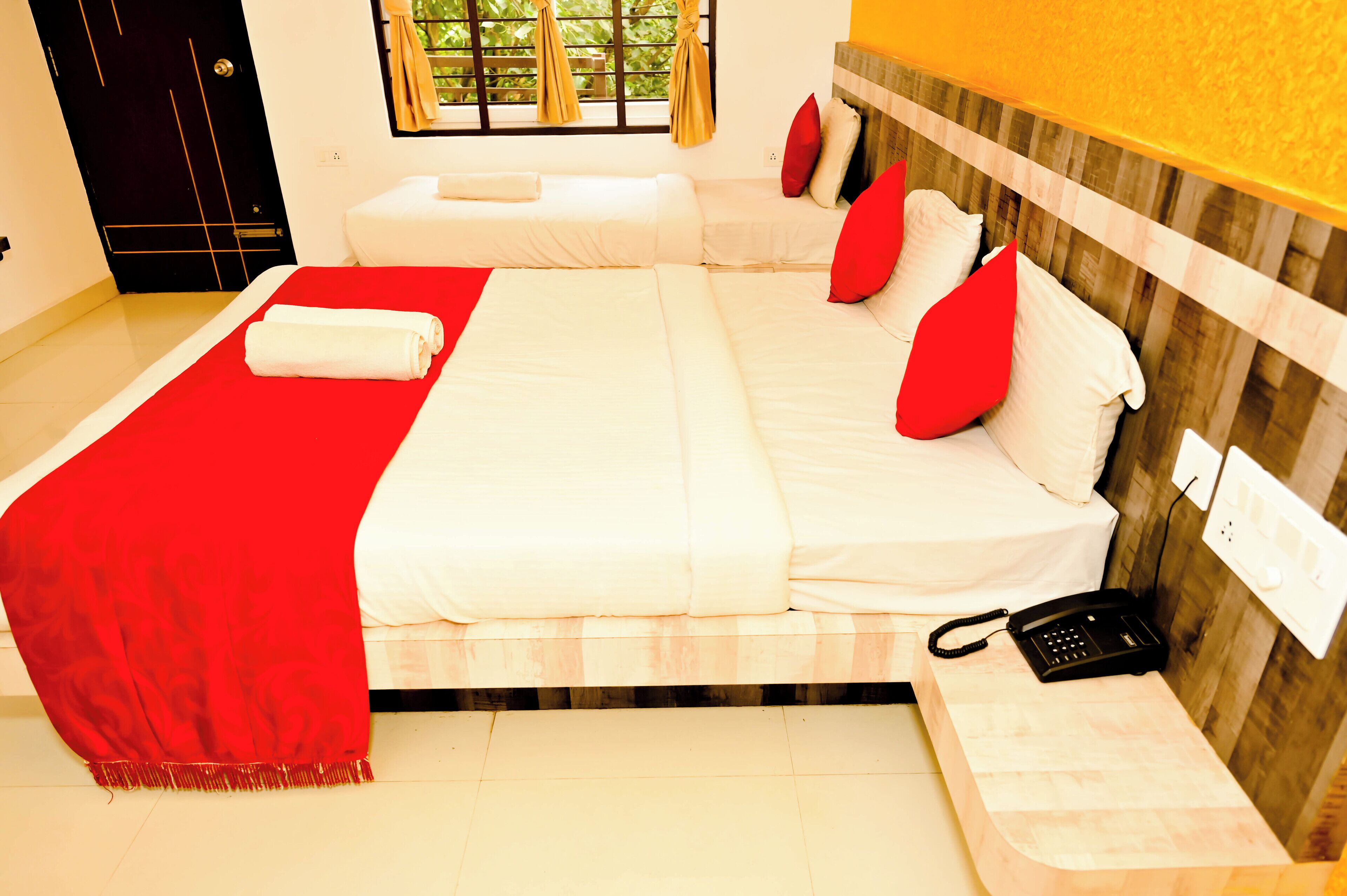Quarto de hotel com cama grande, telefone ao lado da cama e janela com cortinas.