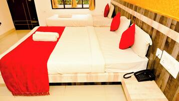 Quarto de hotel com cama grande, telefone ao lado da cama e janela com cortinas.