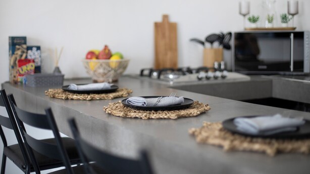 Uma cozinha moderna com uma ilha central, micro-ondas e uma tigela de frutas.