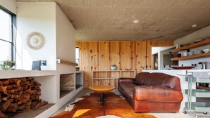 Uma sala de estar moderna com um sofá de couro, uma mesa de centro redonda e um tapete de couro de vaca.