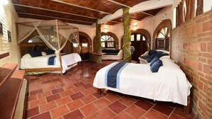 Quarto com duas camas, parede de tijolos e teto de madeira.
