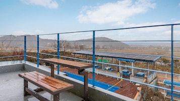 Uma varanda com vista para uma paisagem rural, incluindo campos e montanhas ao longe.
