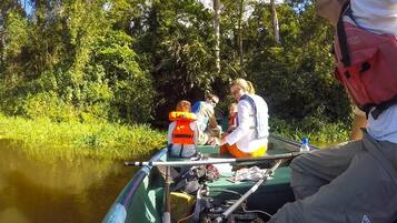 Um grupo de pessoas em um barco, em um rio rodeado por vegetação.