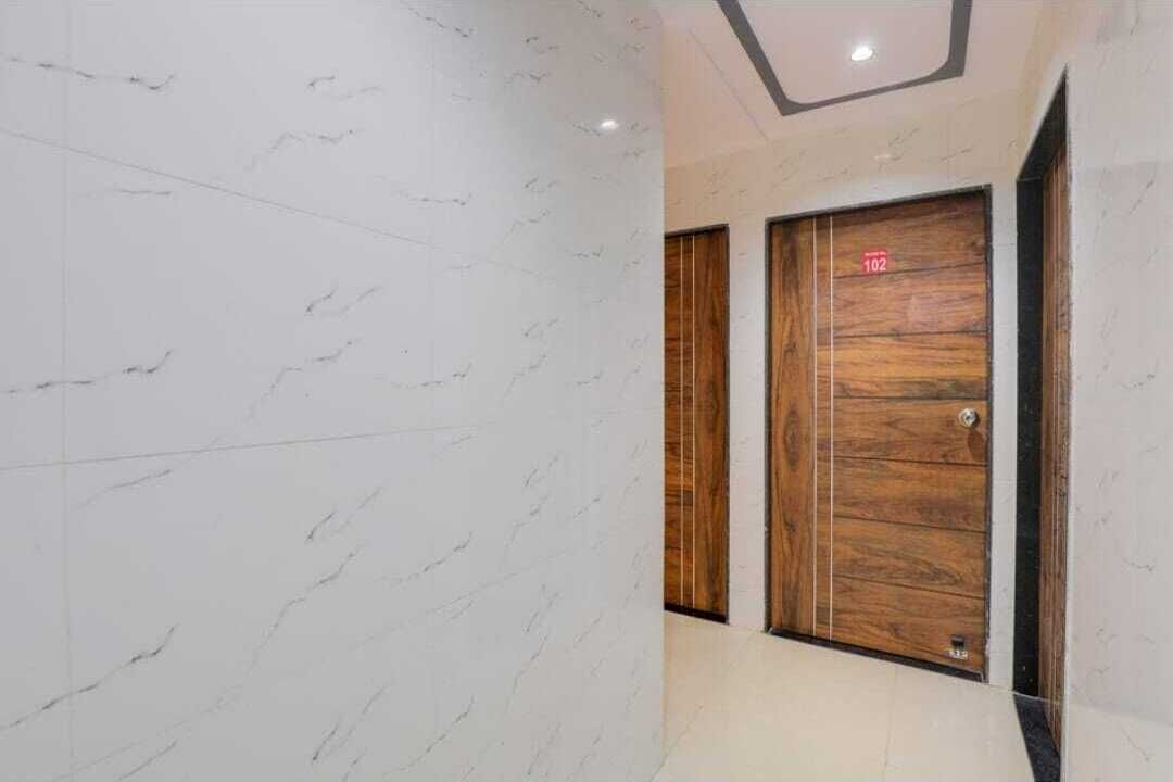 Um corredor com paredes de mármore e uma porta de madeira com um sinal de número.