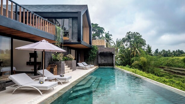 Uma casa moderna com piscina, espreguiçadeiras e uma cascata.