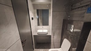 Uma casa de banho moderna com sanita, lavatório e espelho.