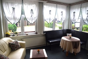 Quarto com sofá, mesa e janela com cortinas.