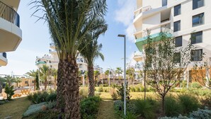 Zona residencial com edifícios modernos, palmeiras e jardins bem cuidados.