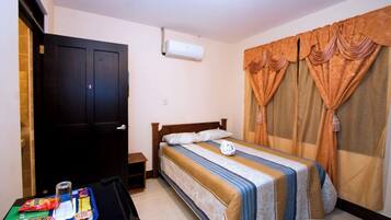 Quarto com cama, guarda-roupa, uma mesinha com petiscos e cortinas.