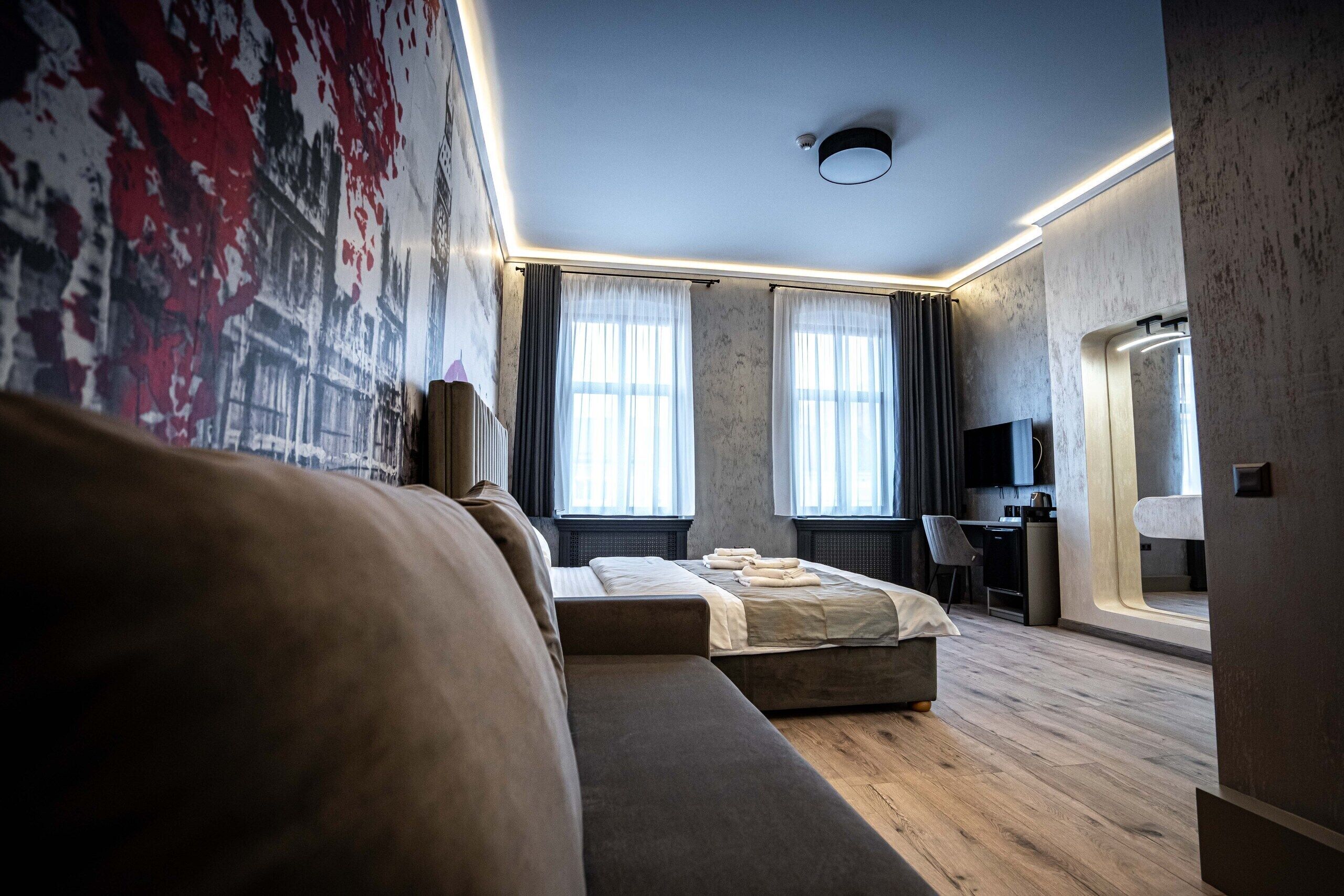Quarto de hotel moderno com uma cama grande, um sofá, uma escrivaninha e uma televisão.