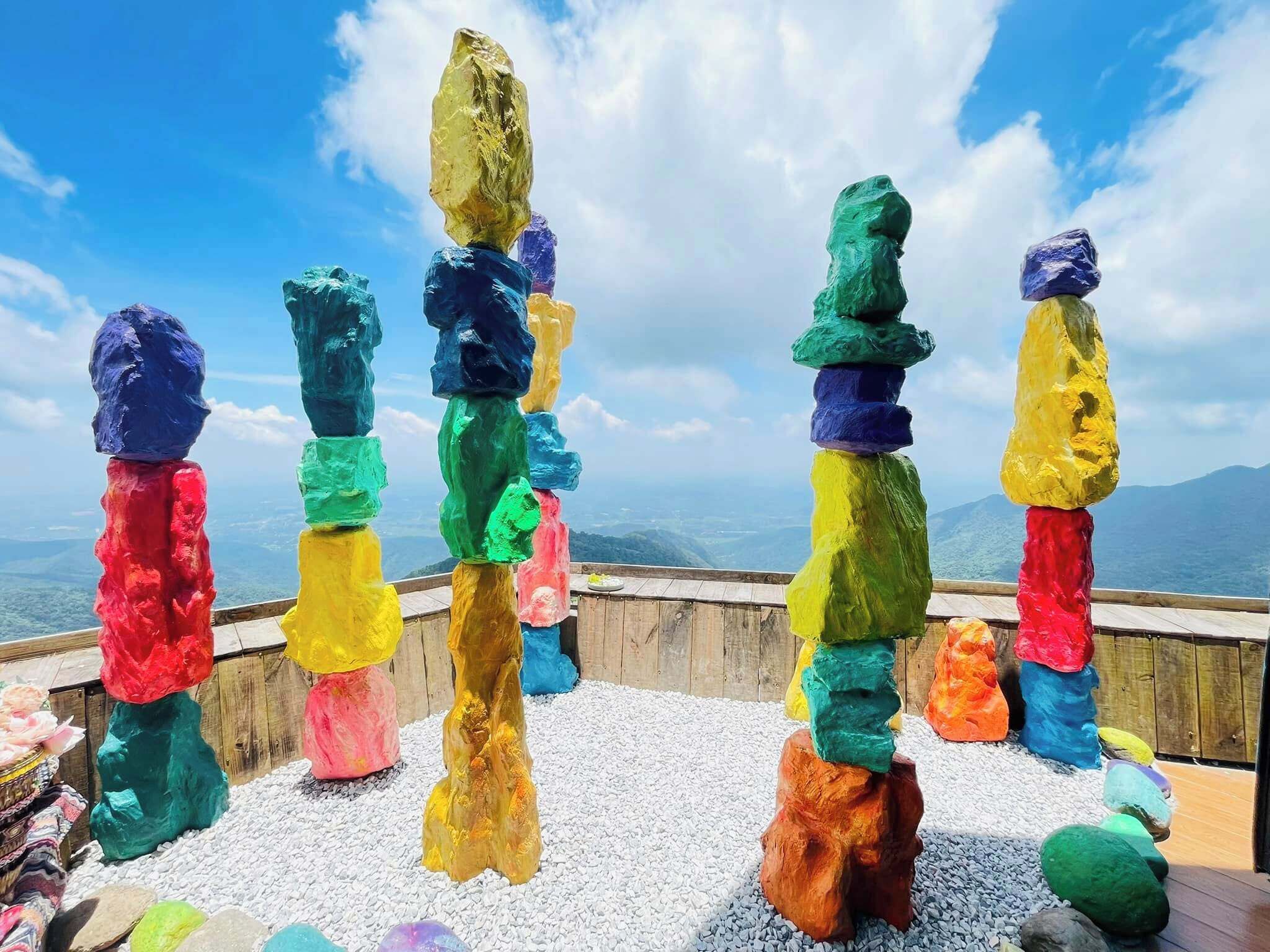 Esculturas rochosas coloridas sobre uma plataforma de madeira com vista panorâmica.
