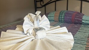 Cama com arranjo de toalhas decorativo e um edredom estampado.