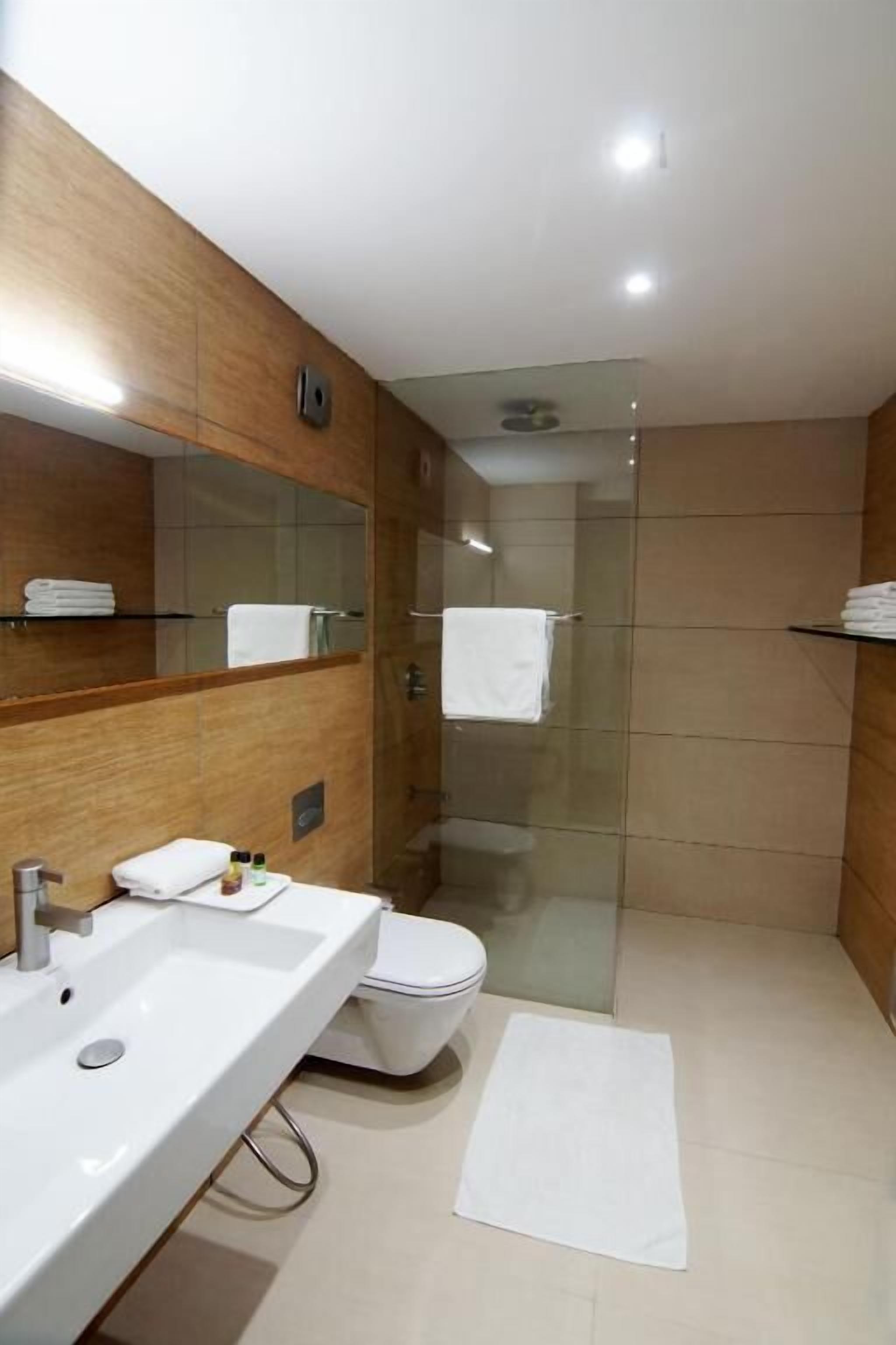 Uma casa de banho moderna com cabine de duche em vidro, uma sanita branca e um espelho em cima.