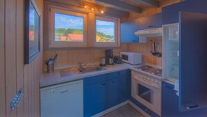 Uma cozinha compacta com paredes de madeira, lava-louças, fogão e micro-ondas.