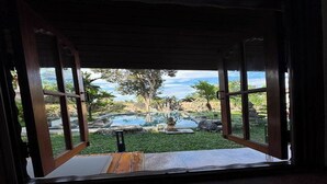 Uma porta de madeira aberta que dá para um quintal com uma piscina pequena, uma construção de pedra e um deck de madeira.
