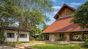 Um edifício de dois andares com telhado de telhas vermelhas, um alpendre coberto e um jardim ajardinado com um caminho de pedra.