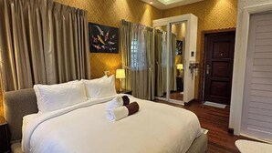Quarto de hotel com cama grande, uma mesa de trabalho e porta para o banheiro.