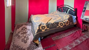 Quarto com cama, mesa de cabeceira, espelho e janela.