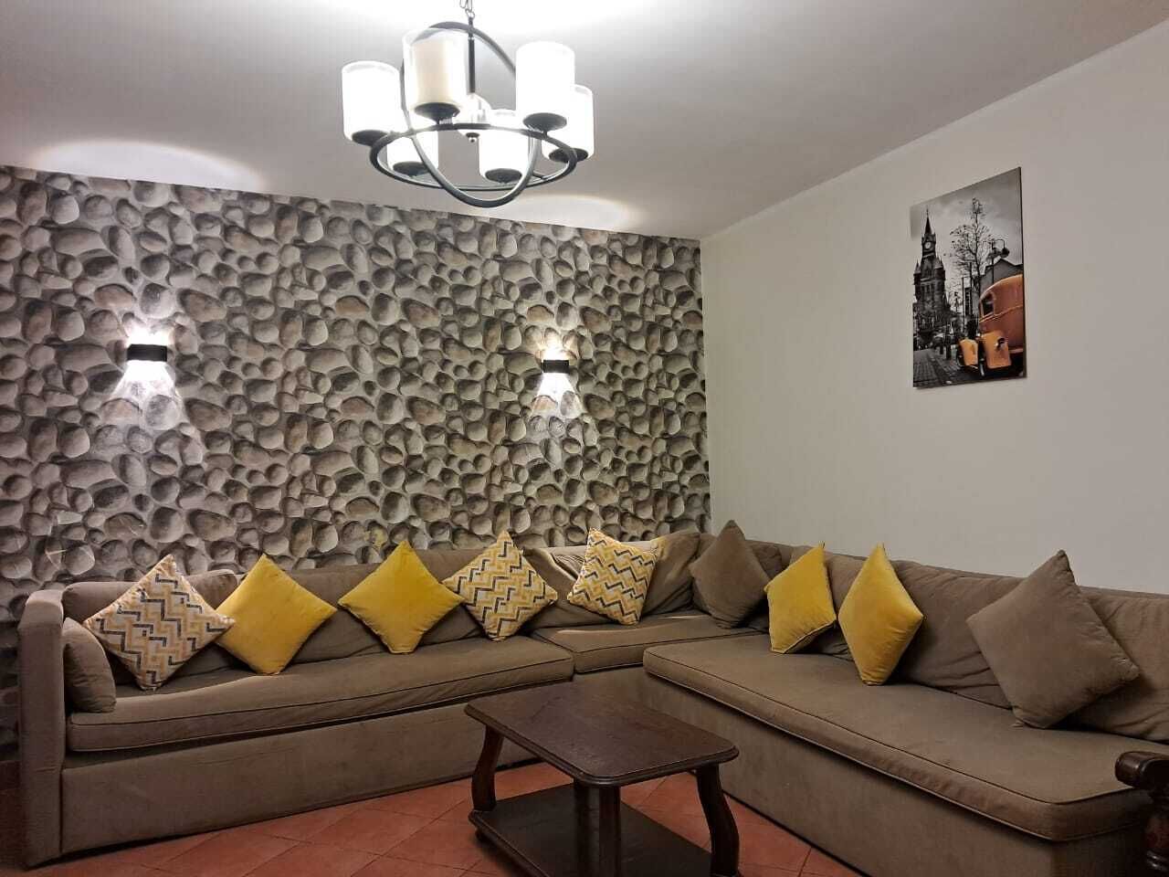 Uma sala de estar com sofá seccional, mesa de centro e parede texturizada.