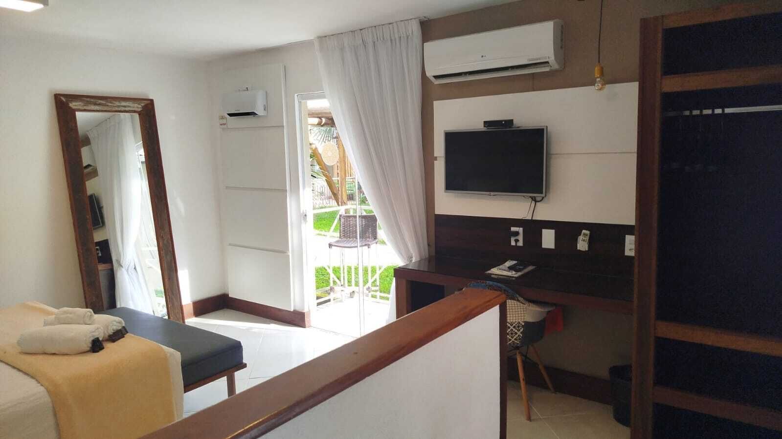 Quarto com mesa de massagem, televisão e ar condicionado.