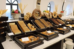 Buffet com diversos alimentos, incluindo pão, doces e sobremesas.