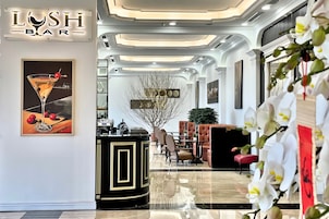 Uma área de bar com uma placa indicando "LUSH BAR", uma obra de arte emoldurada de um copo de martini e um balcão de bar preto e dourado.