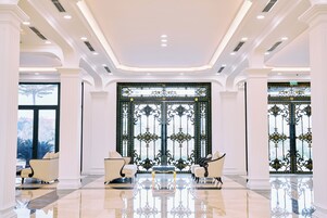 Um hall amplo com tetos altos, janelas grandes e portões de metal preto ricamente decorados.