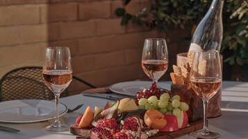 Uma mesa posta para refeição, com copos de vinho, tábua de queijos e uma garrafa de vinho.