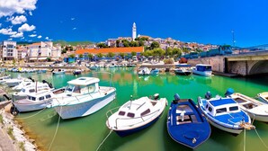Marina com vários barcos atracados, uma ponte e edifícios ao fundo.