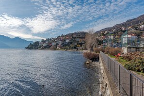 Vista para o lago com uma parede de pedra e um corrimão de metal na orla.