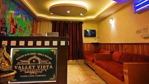 Uma área de recepção com um letreiro para Valley Vista Resort, um balcão de recepção, um sofá, uma TV e um mural colorido na parede.
