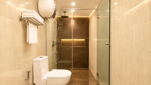 Um banheiro moderno com vaso sanitário, box de chuveiro em vidro e piso de mármore.